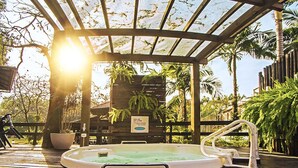 Uma banheira de hidromassagem sob uma pérgula de madeira, com uma placa indicando que é um spa.