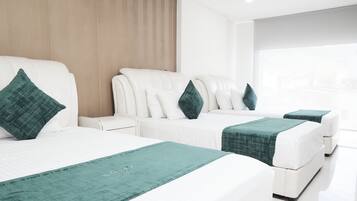 Quarto de hotel com duas camas, cada uma com um cobertor verde e roupa de cama branca.