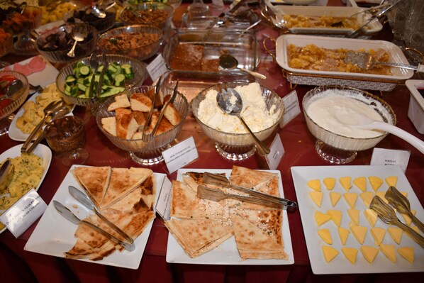 Buffet com diversos pratos, incluindo saladas, pão e queijo.