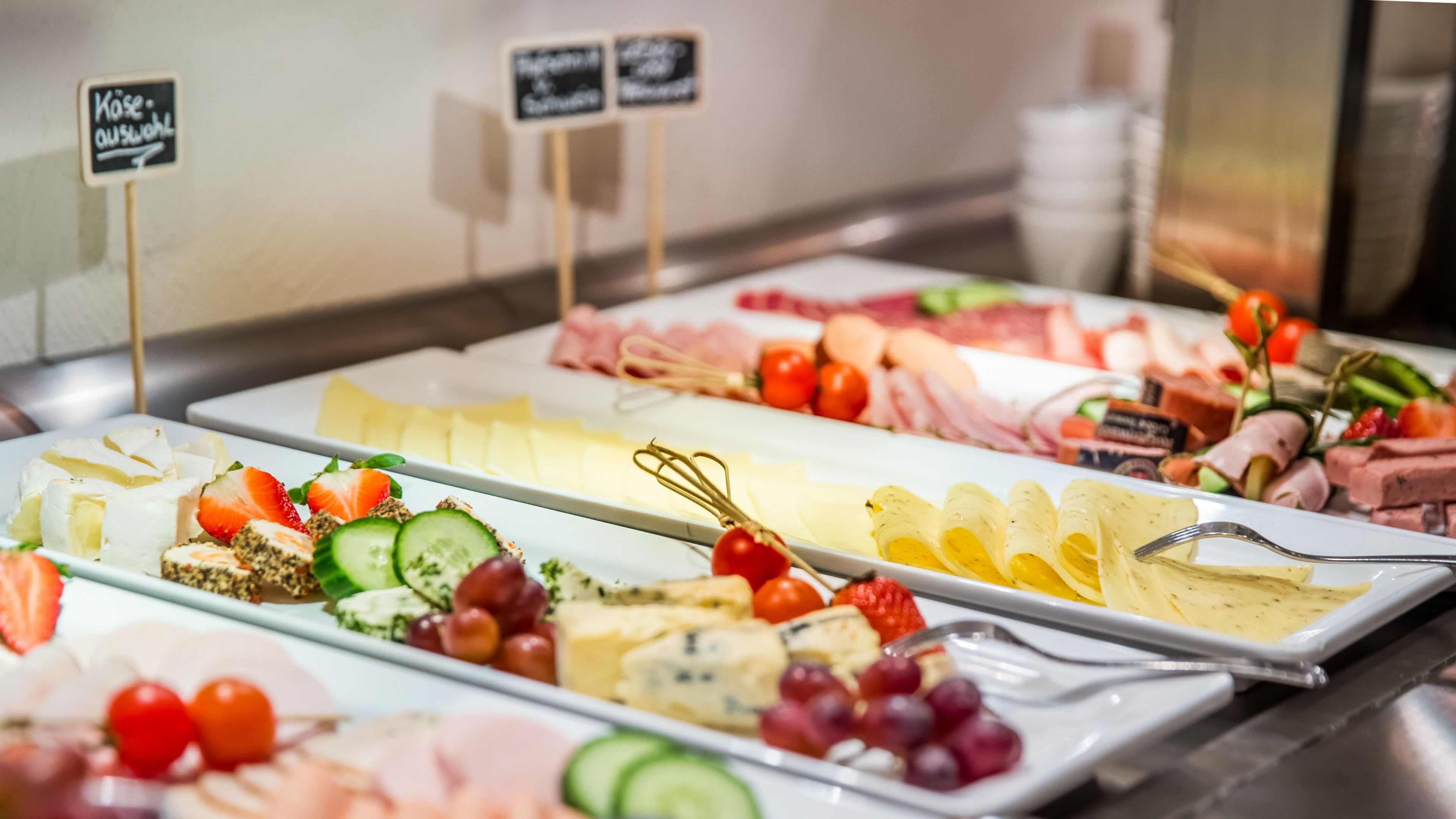 Buffet com diversas opções de comida, incluindo queijos, carnes e frutas.