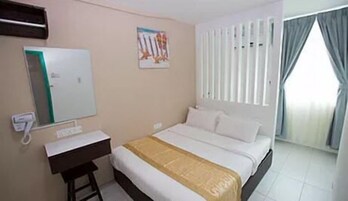 Quarto de hotel com cama, escrivaninha, telefone e janela com cortinas.