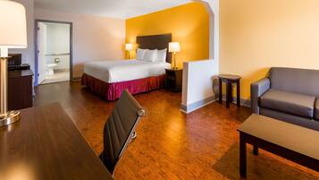 Quarto de hotel com cama, mesas de cabeceira, escrivaninha, cadeira e sofá.
