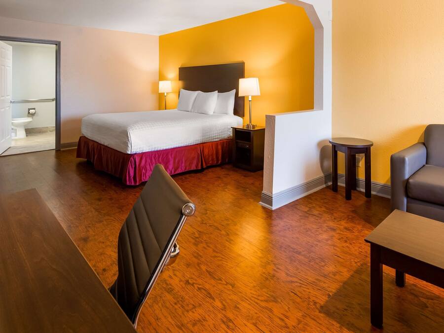 Quarto de hotel com cama, mesas de cabeceira, escrivaninha, cadeira e sofá.