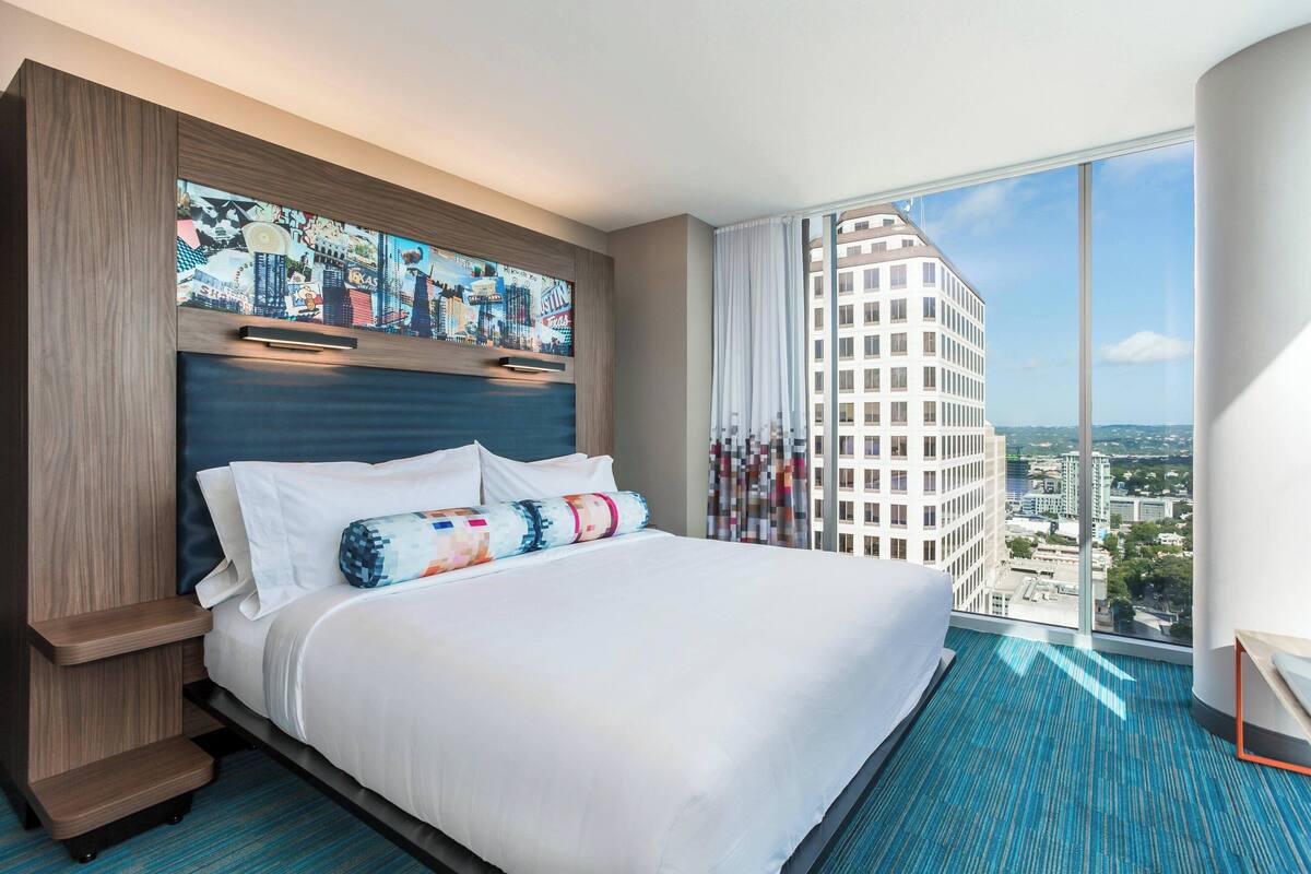 Quarto de hotel com uma cama grande, vista para a cidade e design moderno.