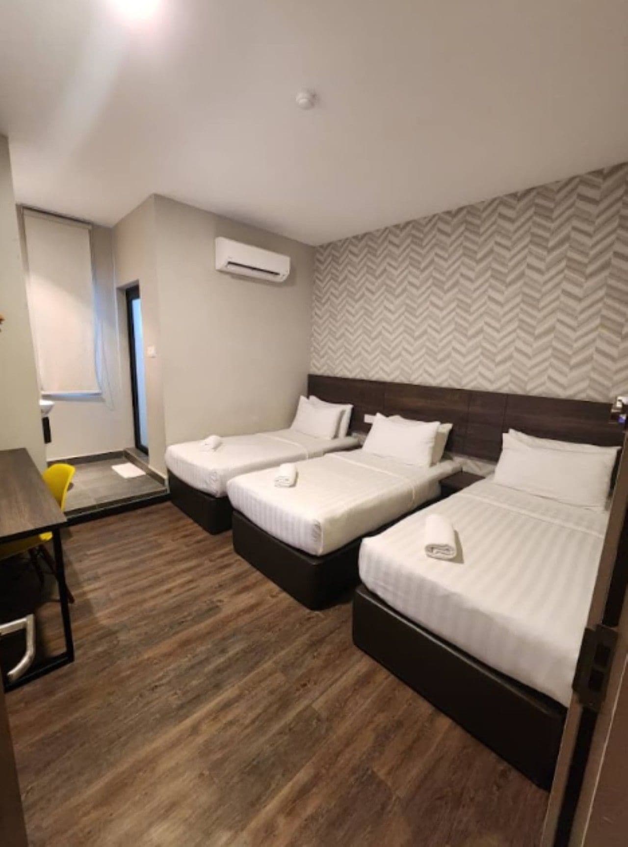 Quarto de hotel com duas camas, uma mesa e uma cadeira.