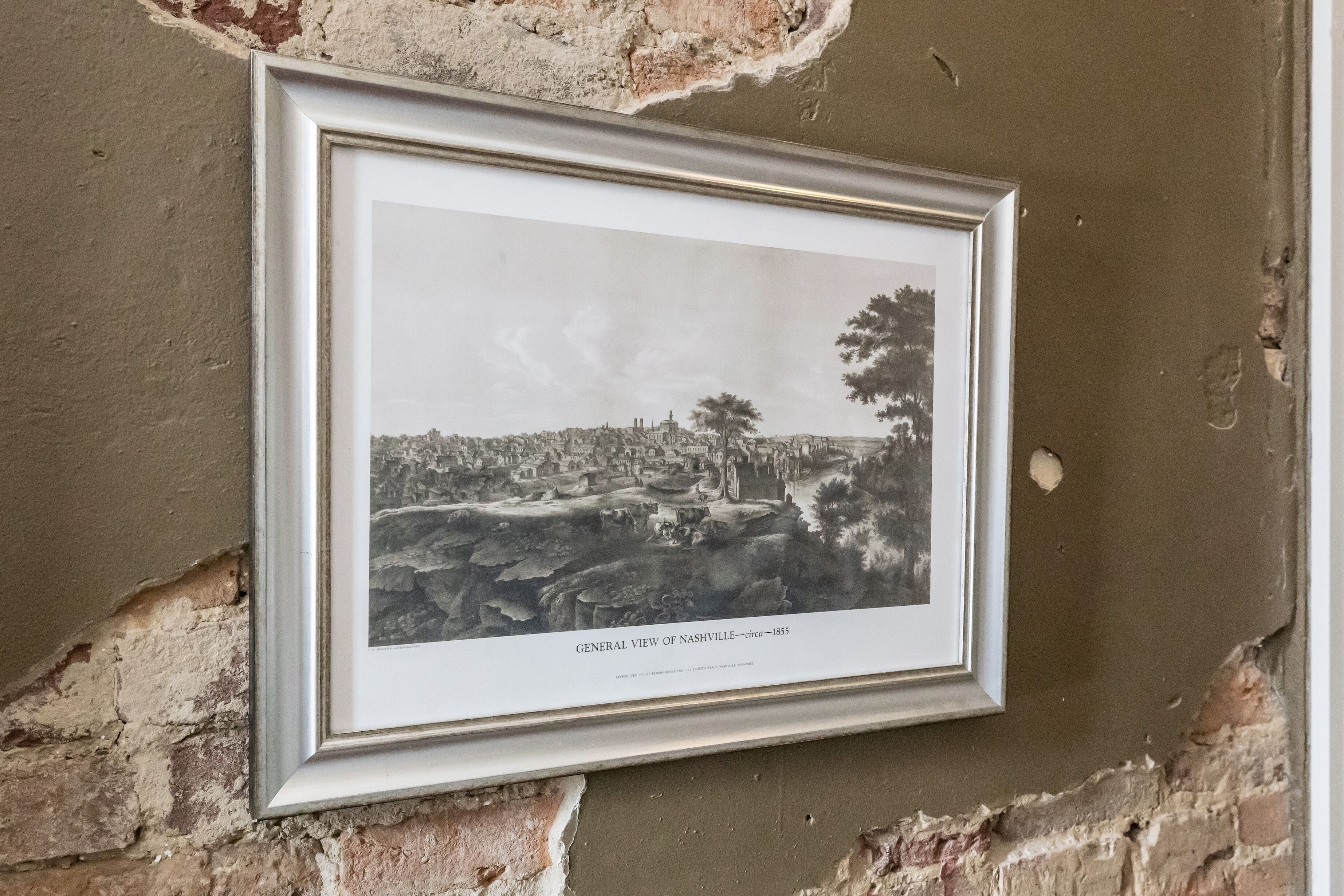 Fotografia em preto e branco emoldurada mostrando uma vista urbana com edifícios e árvores, com a legenda 'General View of Nashville circa 1855'.