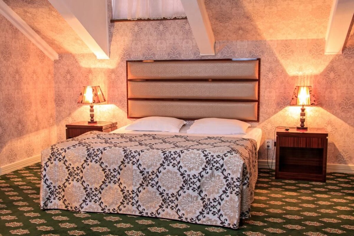 Quarto com uma cama grande, duas mesas de cabeceira e luminárias.