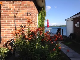 Edifício de tijolos com o número 15, um pátio com guarda-sol vermelho e vista para um lago.