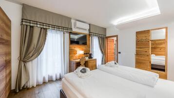 Quarto de hotel com cama, escrivaninha com luminária, espelho e guarda-roupa.