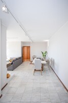 Uma sala de estar moderna com área de jantar, com sofá, mesa de jantar e cadeiras.