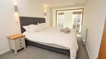 Quarto com cama, mesa de cabeceira e janela.