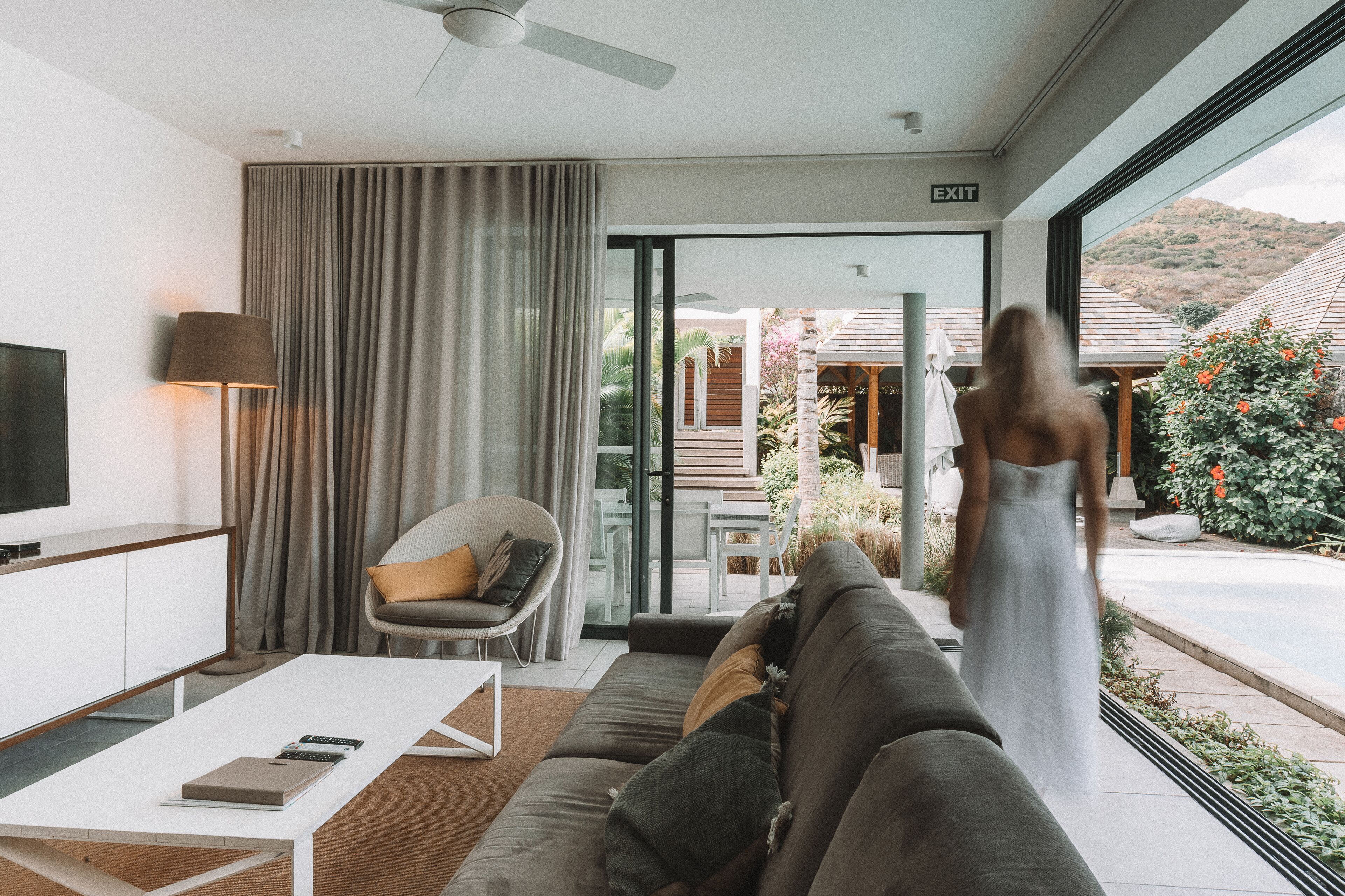 Quarto de hotel moderno com sofá, mesa de centro, TV e uma janela grande com vista para o exterior.