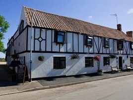 Um edifício tradicional em estilo de enxaimel, com telhado de telhas, várias janelas e área de estar ao ar livre.