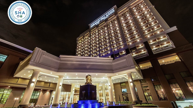 Um hotel com entrada imponente, uma fonte central e fachada bem iluminada.