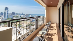 Varanda com vista para a cidade, mobiliada com mesas e cadeiras, e grade de metal.