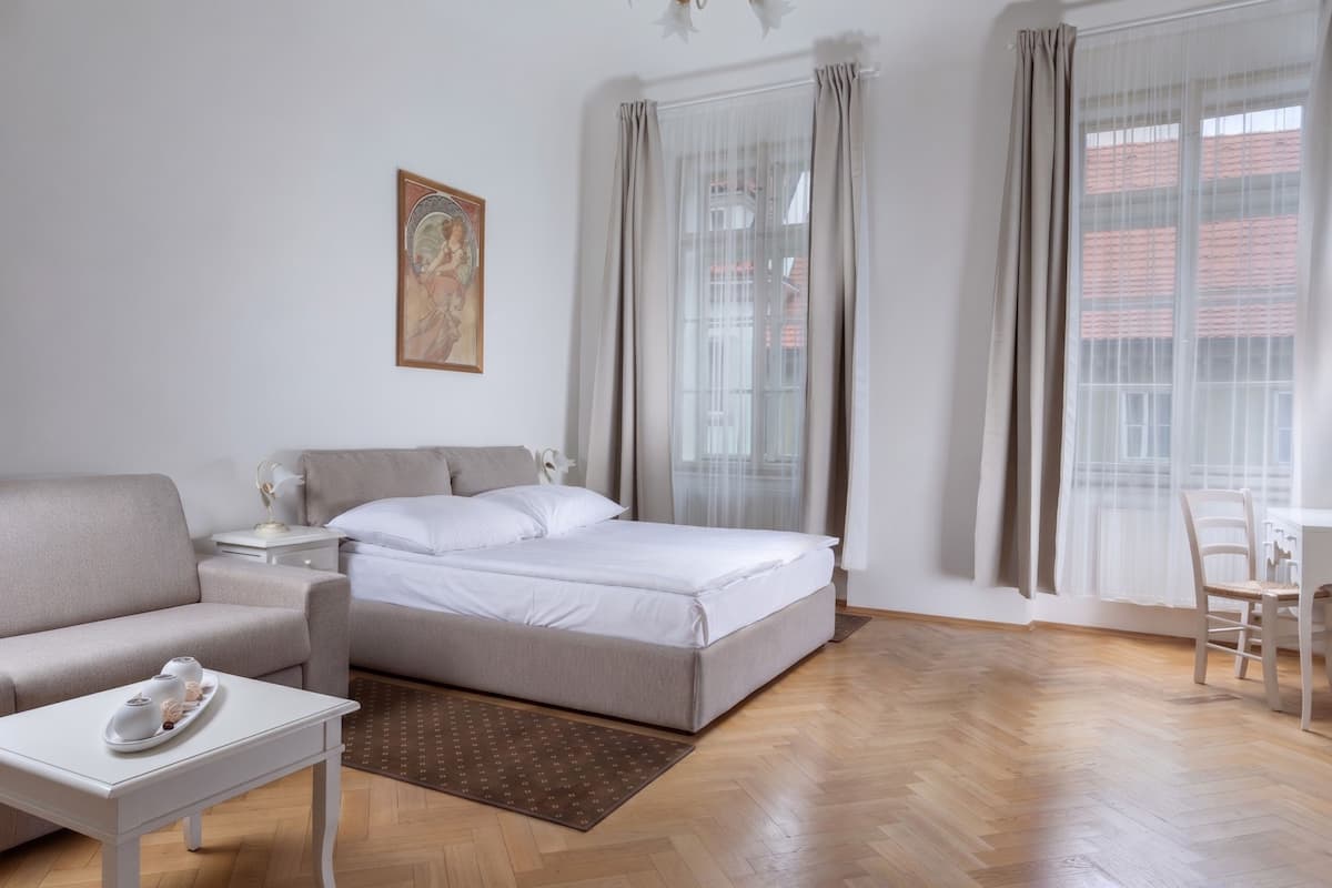 Quarto com cama, sofá, mesinha e uma cadeira.