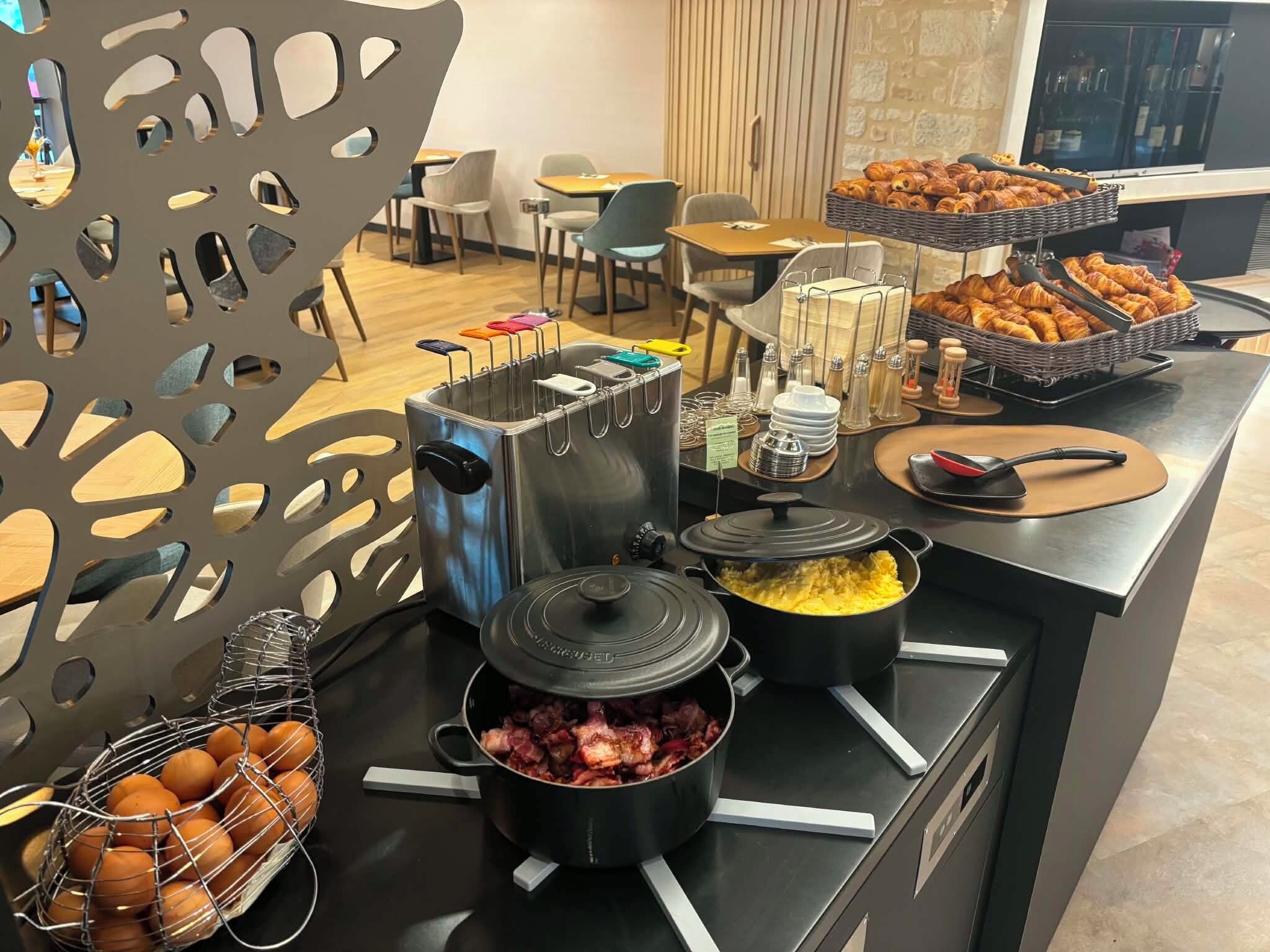 Disposição de buffet com diversos pratos, estações de cozinha e arranjos de mesas.