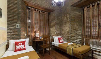 Quarto com duas camas, móveis de madeira e parede de tijolos.