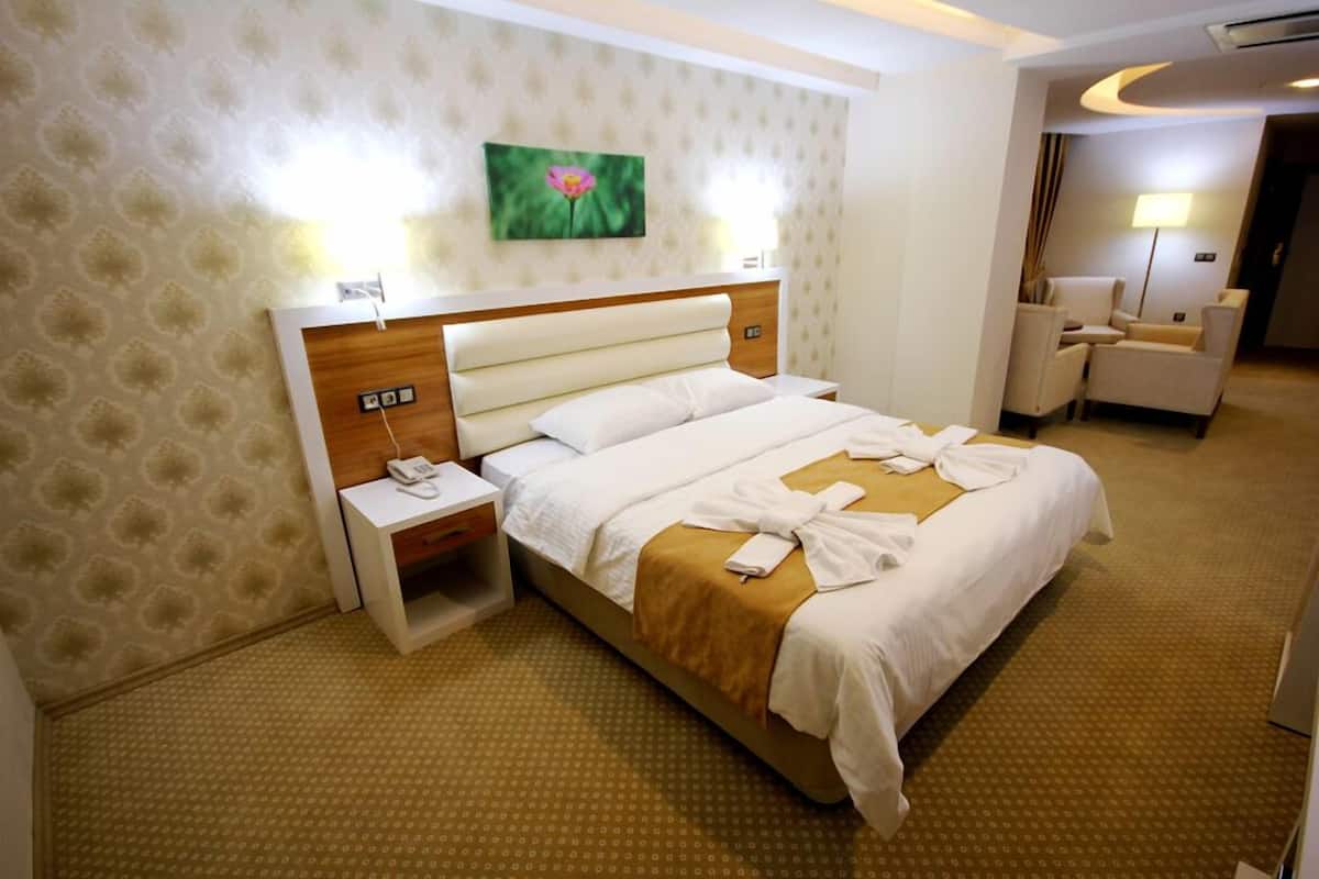 Quarto de hotel com uma cama, mesa de cabeceira, abajur e uma cadeira.