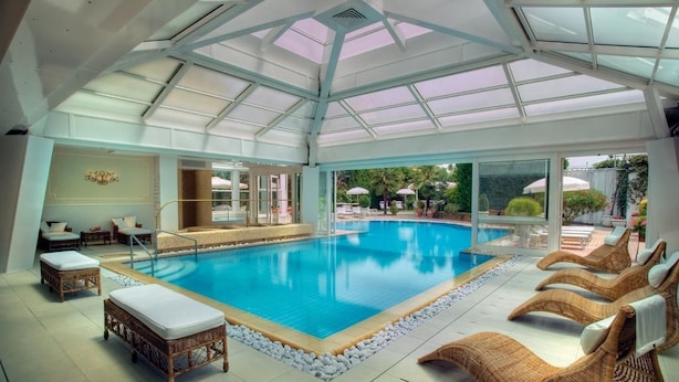 Uma grande piscina coberta com espreguiçadeiras e teto de vidro.