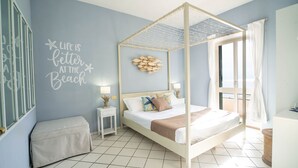 Quarto com cama de dossel, uma pequena mesa de cabeceira, um criado-mudo, um banco e uma parede com arte de parede decorativa de peixes e uma frase motivacional.