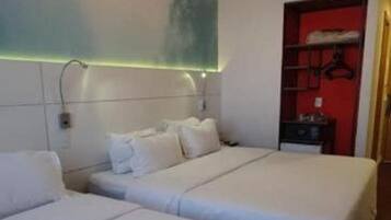 Quarto de hotel com duas camas, uma porta vermelha e luminária fixada na parede.