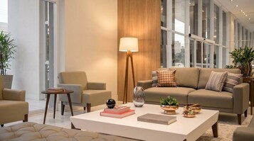 Uma sala de estar moderna com sofá, poltronas, mesa de centro e luminária de chão.