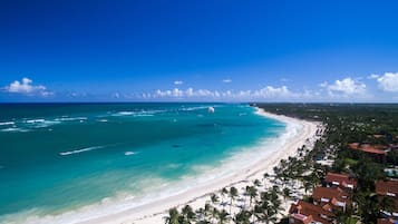 Na praia, areia branca, espreguiçadeiras, guarda-sóis