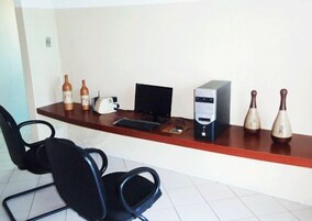 Bancada de recepção com computador, impressora e duas garrafas decorativas.