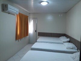 Quarto pequeno e limpo com duas camas de solteiro, um ventilador de teto e um aparelho de ar condicionado.
