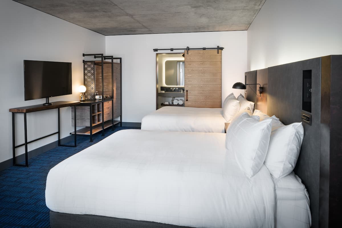 Quarto de hotel com uma cama grande, escrivaninha com televisão de tela plana, espelho e armário com portas de correr.