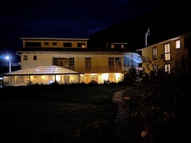 Um edifício de dois andares com uma estufa de vidro, uma varanda e uma entrada bem iluminada.