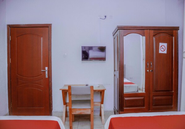 Quarto com guarda-roupa de madeira, escrivaninha e cama.