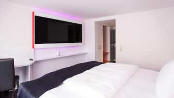Quarto de hotel moderno com uma cama grande, televisão de tela plana na parede, escrivaninha com cadeira e closet espaçoso.