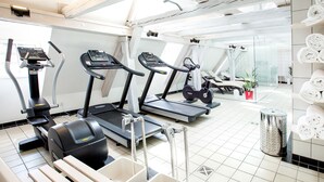 Uma academia com esteiras, bicicleta ergométrica e remo.