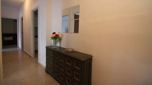 Um corredor com um console de madeira escura, um espelho e um vaso com flores.