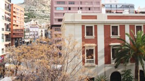 Paisagem urbana com edifícios, incluindo um prédio vermelho e branco de destaque, com janelas em arco e uma varanda.