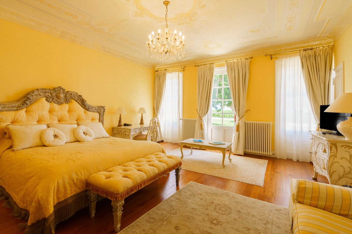 Quarto espaçoso com uma cama grande, um candelabro e vista para o exterior pela janela.