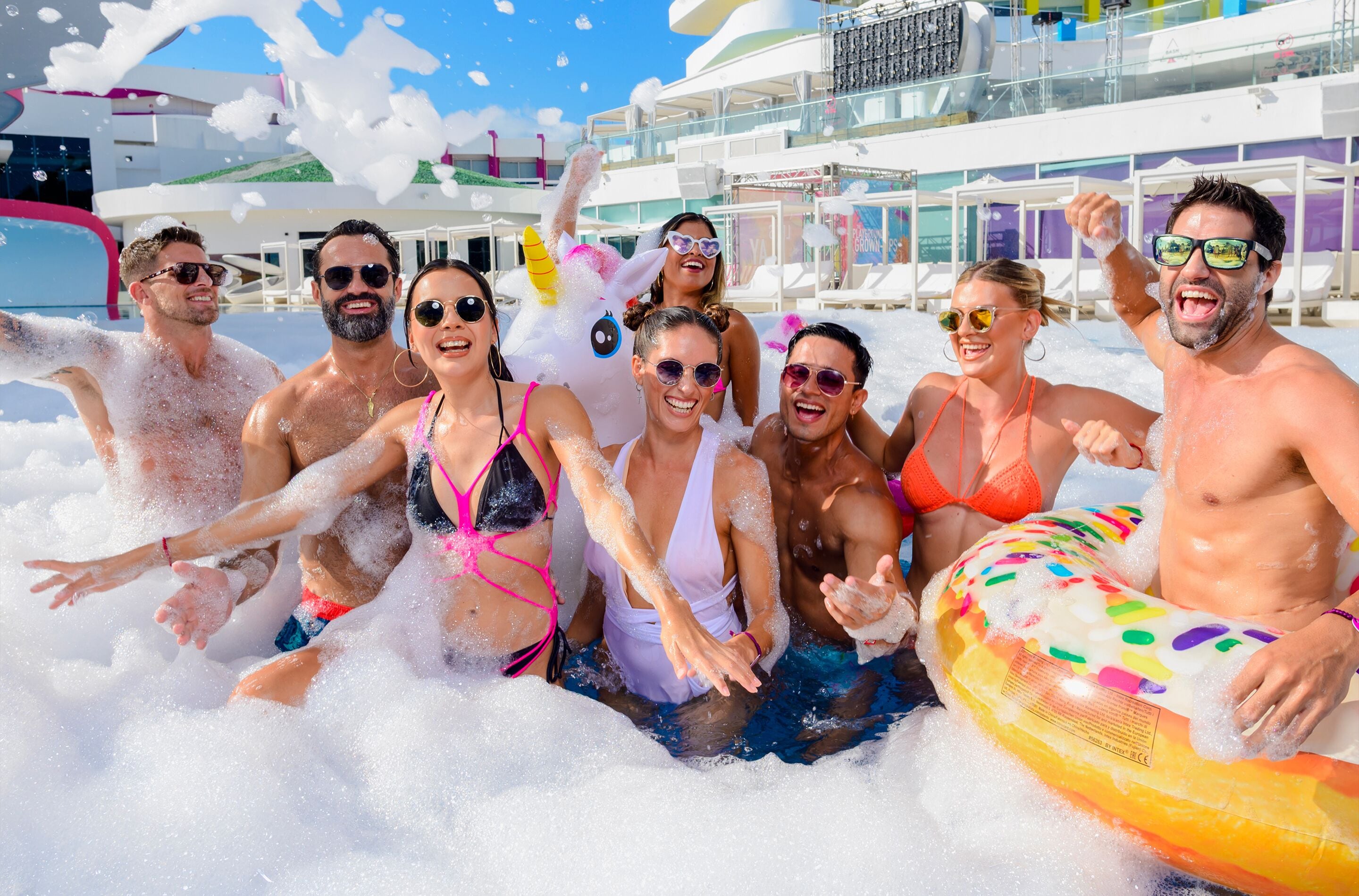 Um grupo de pessoas desfrutando de uma atividade aquática no convés de um navio de cruzeiro, com uma piscina e área de estar ao fundo.