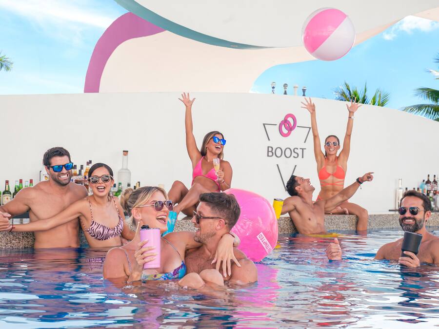Um grupo de pessoas em uma piscina, com um letreiro 'BOOST' ao fundo.