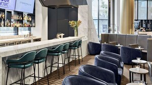 Uma área de bar moderna com balcão de mármore, banquetas e assentos.
