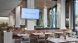 Interior moderno de restaurante, com um balcão longo, cabines e mesas.