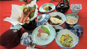 Uma refeição tradicional japonesa com diversos pratos e utensílios sobre uma toalha vermelha.