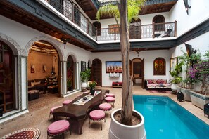 Um pátio com piscina, áreas de estar e uma mesa de jantar.