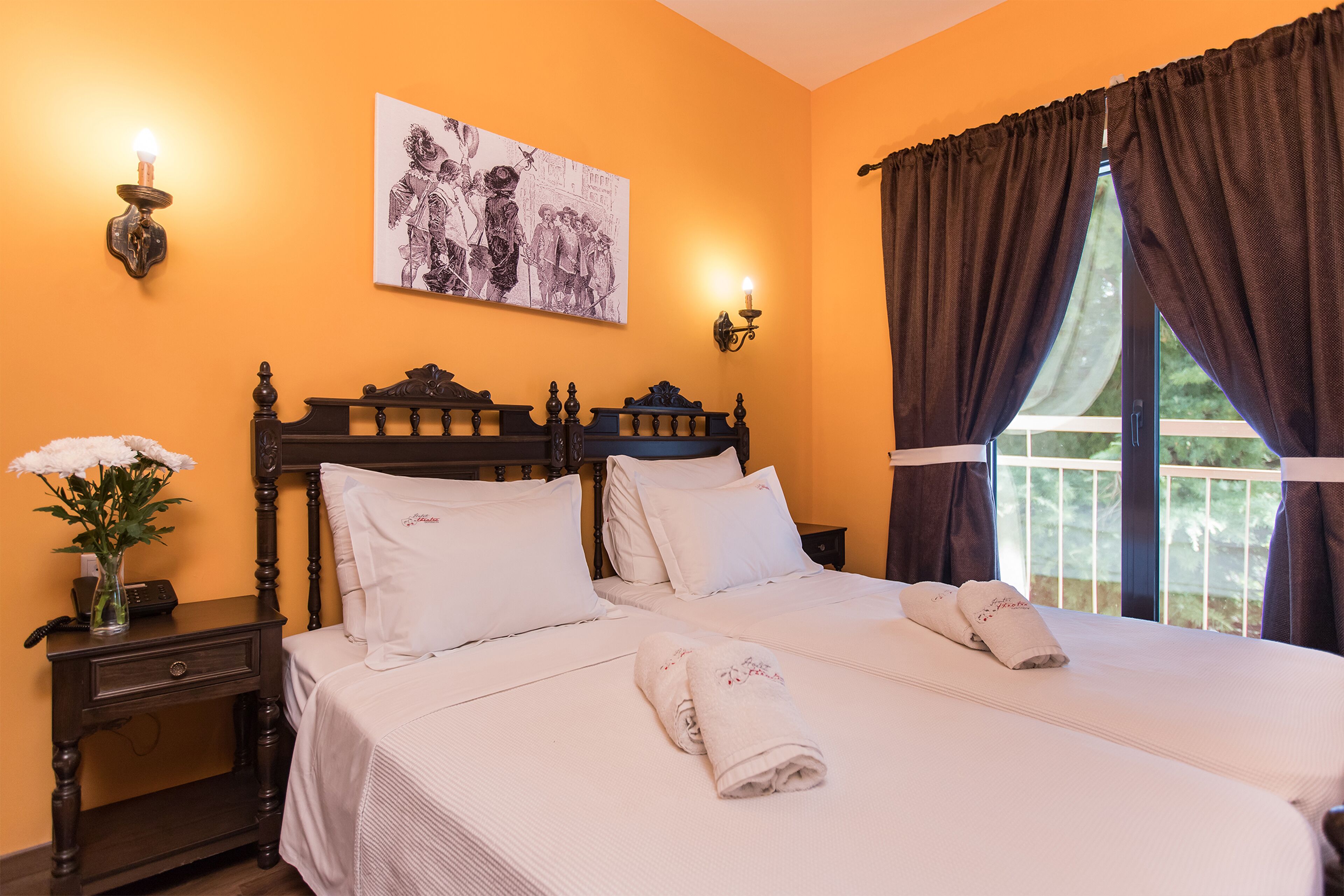 Cama bem arrumada com lençóis brancos, mesa de cabeceira com um vaso de flores e uma obra de arte pendurada na parede.