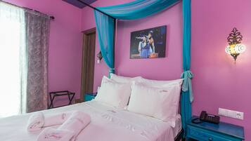 Quarto com cama, mesa de cabeceira, luminária na parede e um quadro.