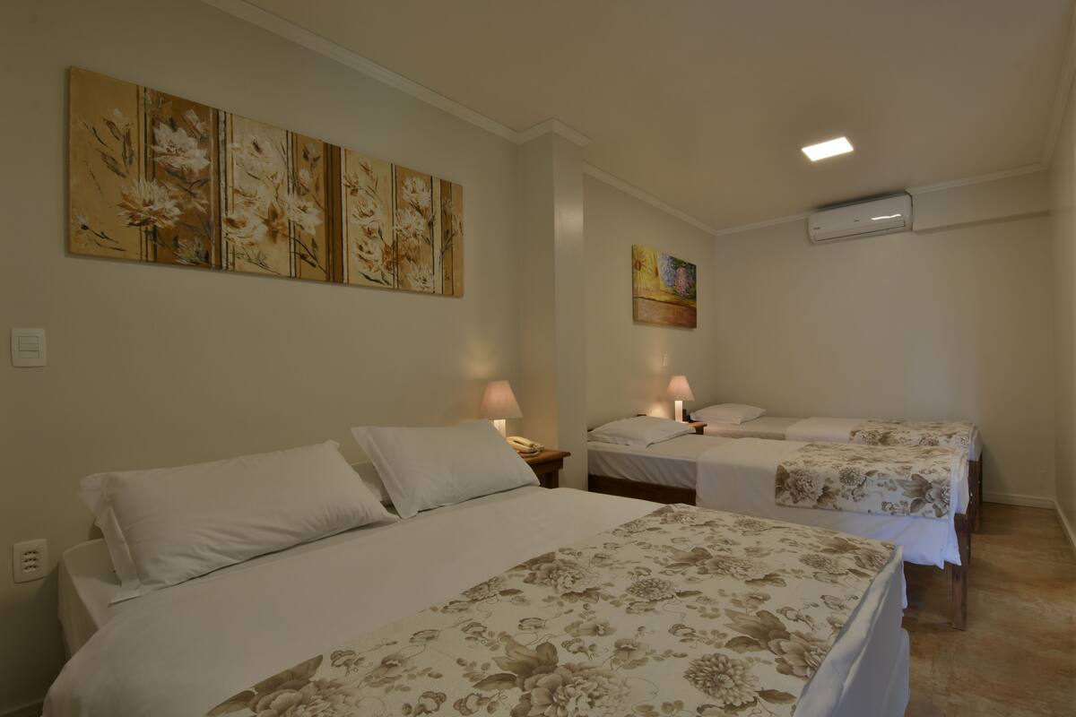 Quarto de hotel com duas camas, um quadro na parede e aparelho de ar condicionado.