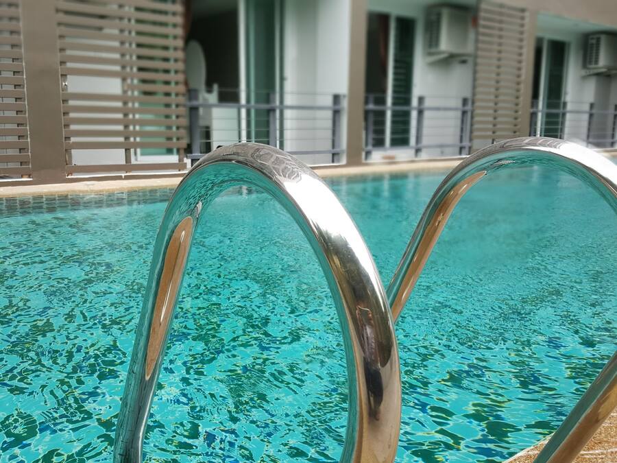 Piscina com água cristalina e escadas de metal.