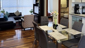 Uma sala de estar moderna com sofá, mesa de jantar, cadeiras e uma área de cozinha com armários e máquina de café.