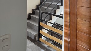 Escada com corrimão de madeira e grades de metal, conduzindo a um andar superior.